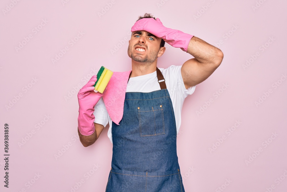 Young cleaner man with blue eyes cleaning wearing apron and gloves ...
