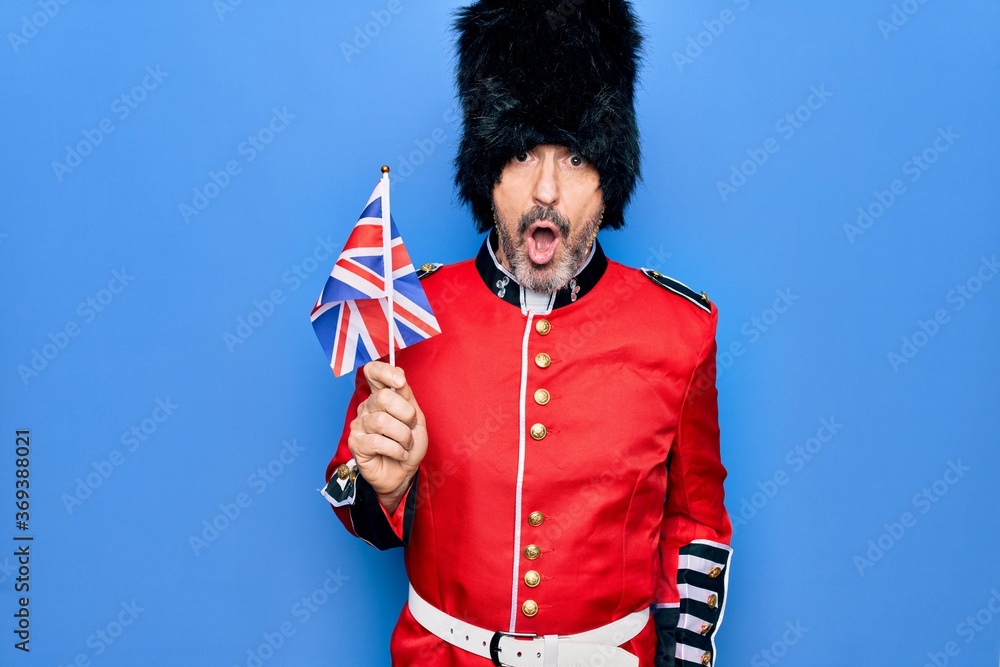 Middle age handsome wales guard man wearing traditional uniform holding ...