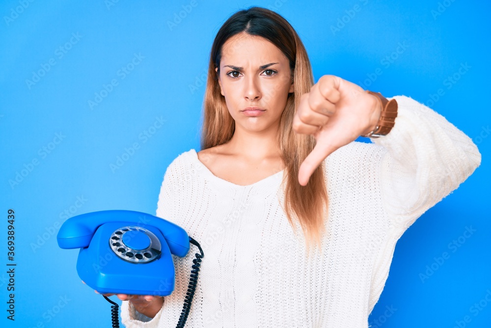 Young brunette woman using vintage telephone with angry face, negative ...