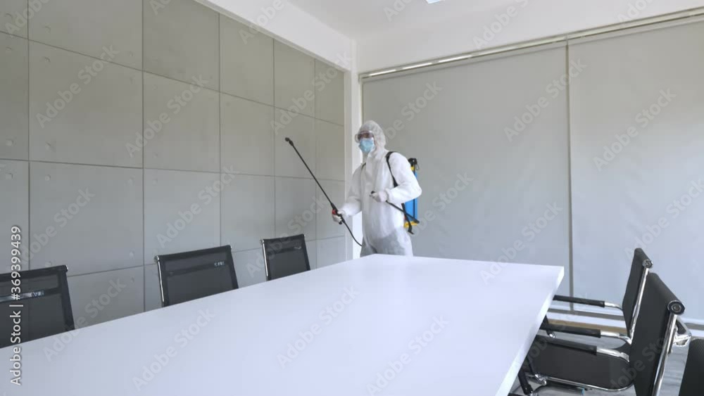Worker in personal protective equipment (ppe) suit cleaning in building ...