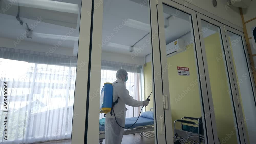 Worker in personal protective equipment (ppe) suit cleaning in building ...