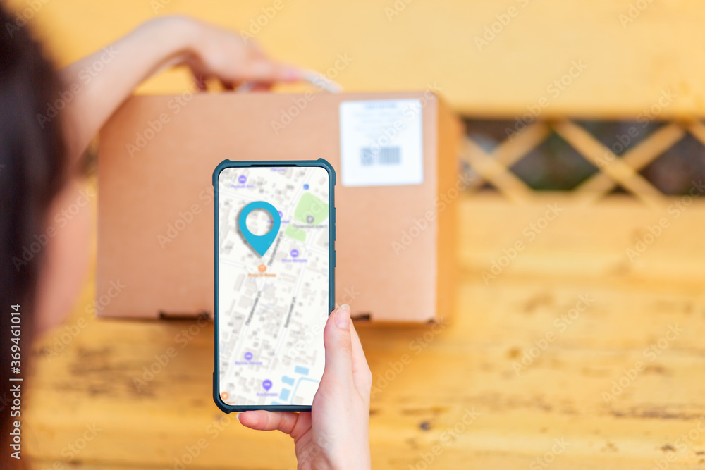 A woman scans the parcel code using her smartphone. Online map on the ...