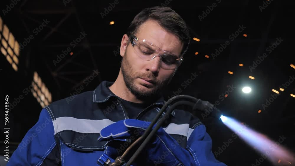 Portrait of serious concentrated professional welder working at factory ...