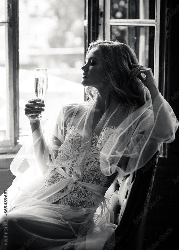 Black and white portrait of elegant bride sitting in front of window ...