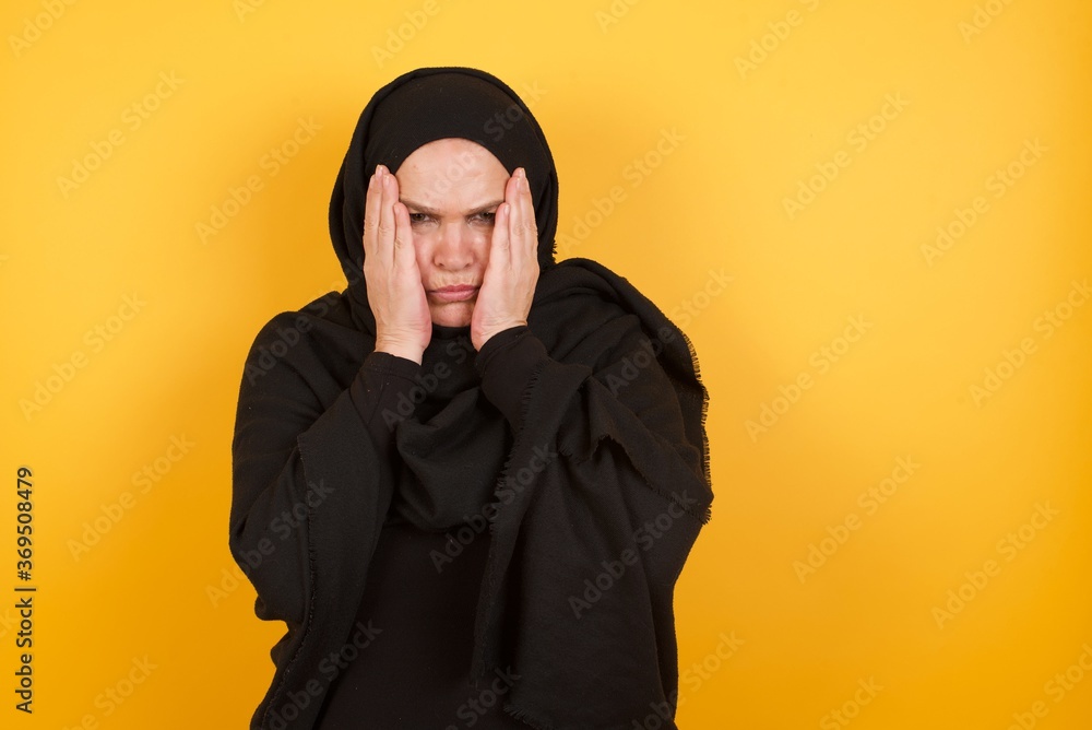 Middle aged muslim woman wearing black hijab over yellow background ...