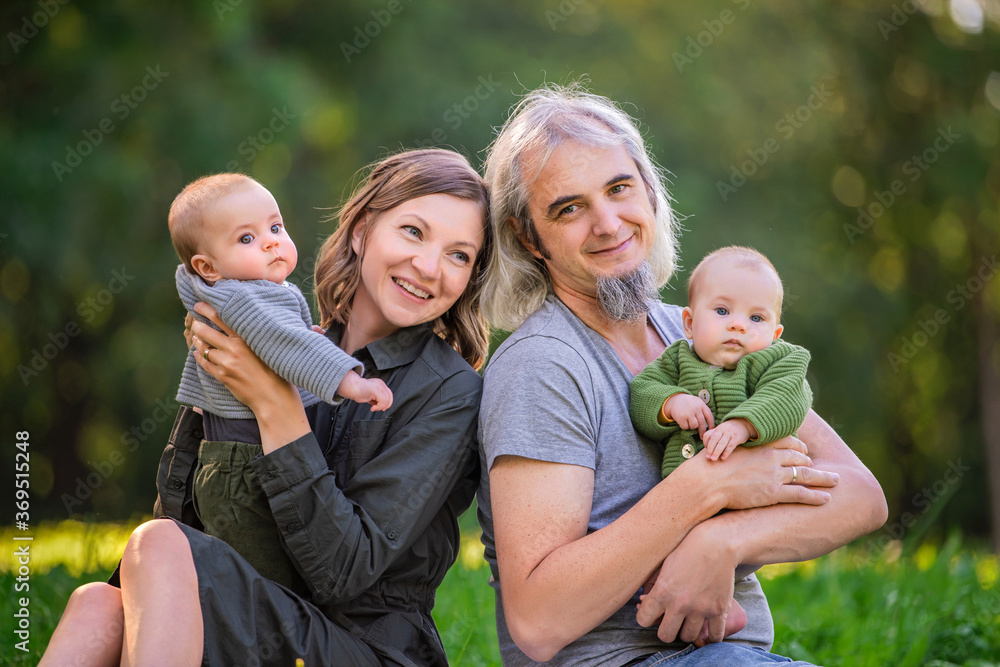 happy married couple with two little twins resting in nature. Portrait ...