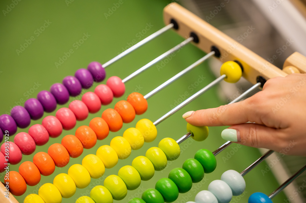 Closeup female hand calculating with balls on wooden rainbow abacus for ...