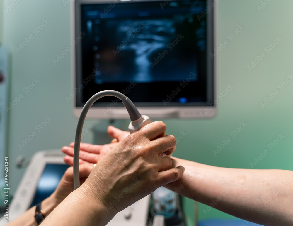 Ultrasound scanning of patient's hand. Modern medical office background ...