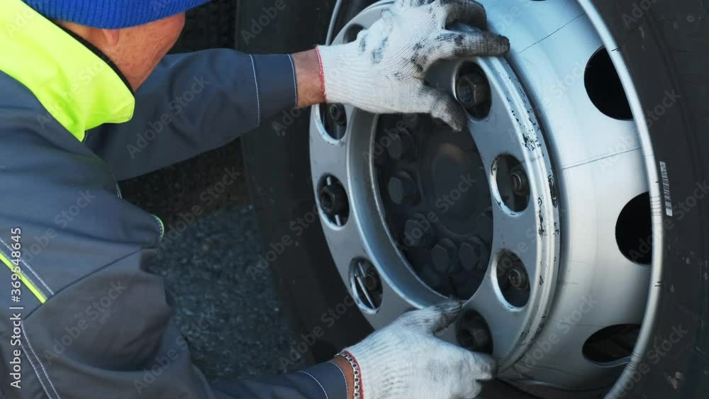 Mechanic twists dirty screw hand on wheels delivery vehicle. Worker ...