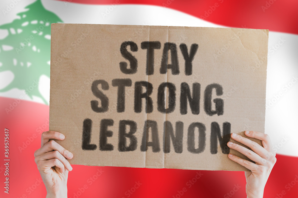 The phrase " Stay strong Lebanon " on a banner in men's hand with ...