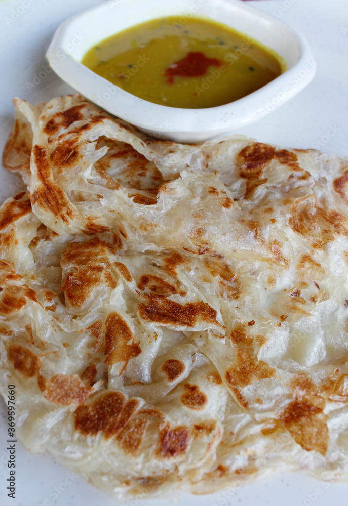Roti canai or pan fried flatbread consisting of dough, egg, ghee and ...