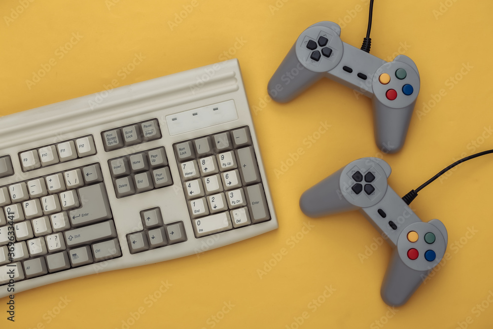 Old pc keyboard and gamepads on yellow background. Retro gaming. Video ...