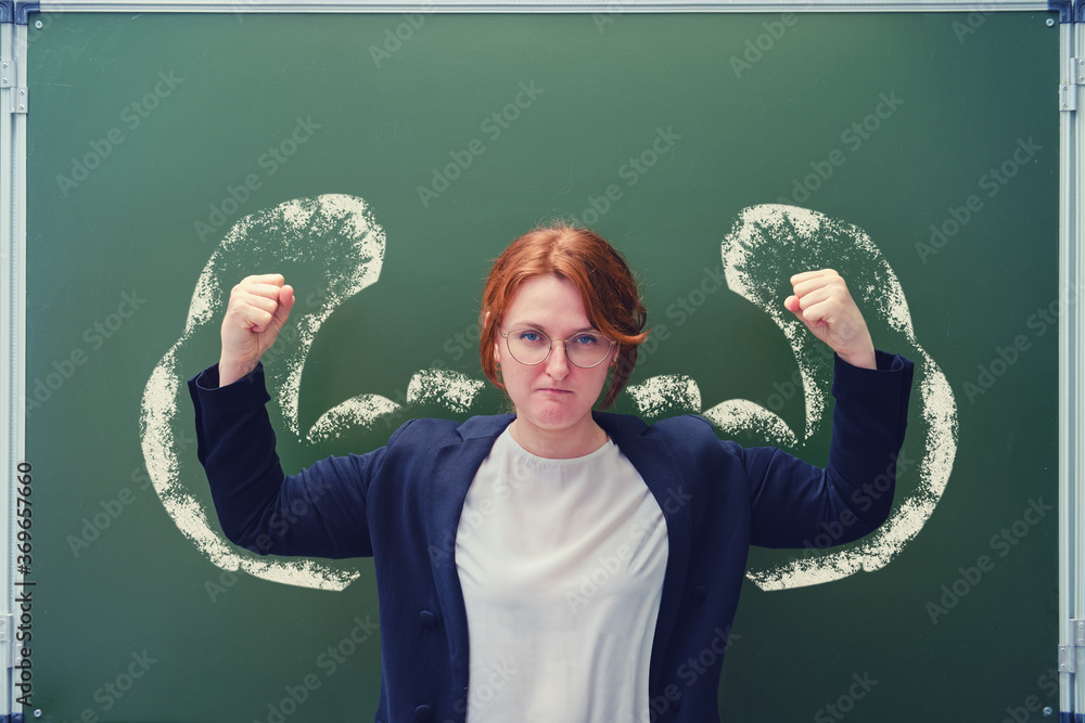 School teacher raised her hands to show strength at the blackboard. A ...