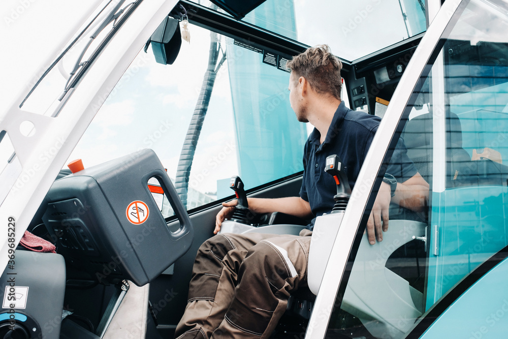 a car with an unrecognizable operator of a large blue crane that stands ...