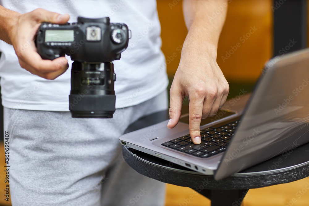 A young man stands outdoors with a camera and takes off a photo on a ...