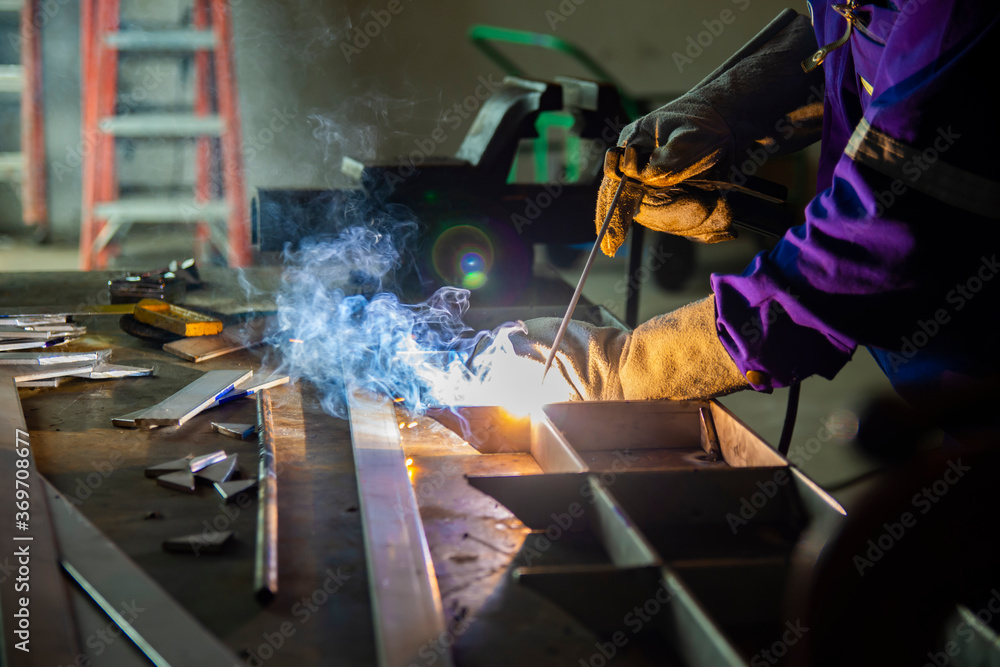 Welder is assembling the workpiece by process shielded metal arc ...