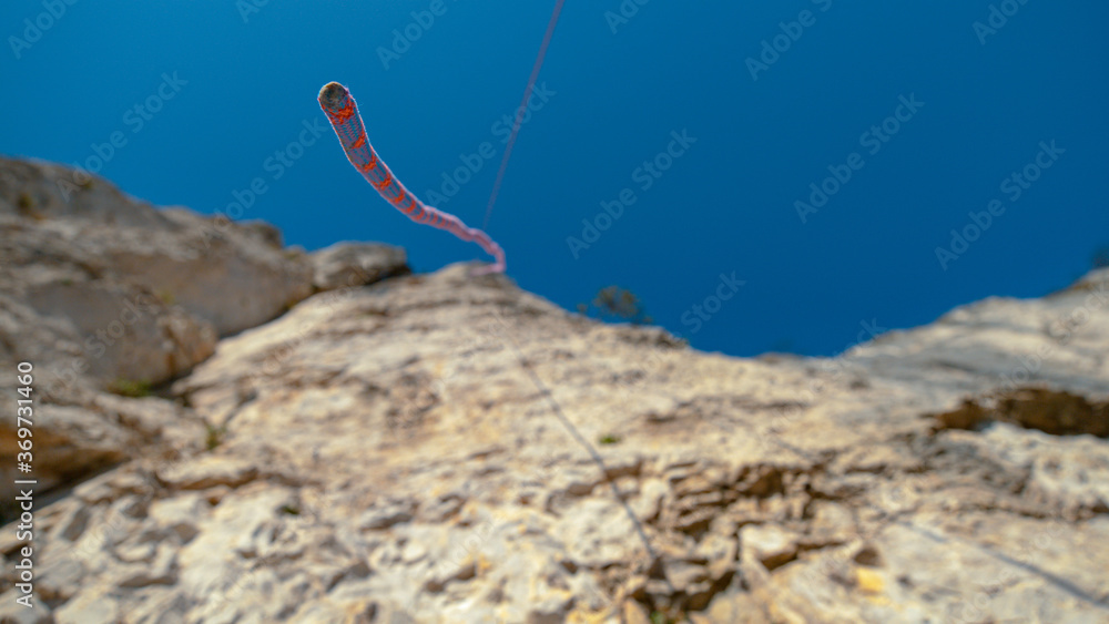 BOTTOM UP, DOF: Blue and red ropes hang from the top of a towering ...