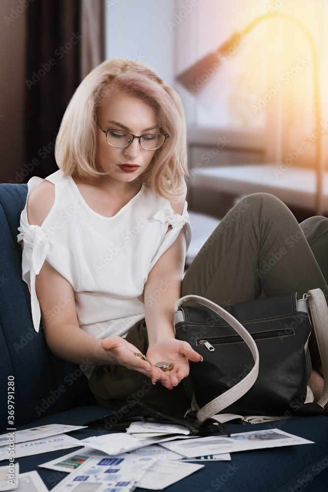 Stressed young woman holding coins in her hands, worrying about paying ...