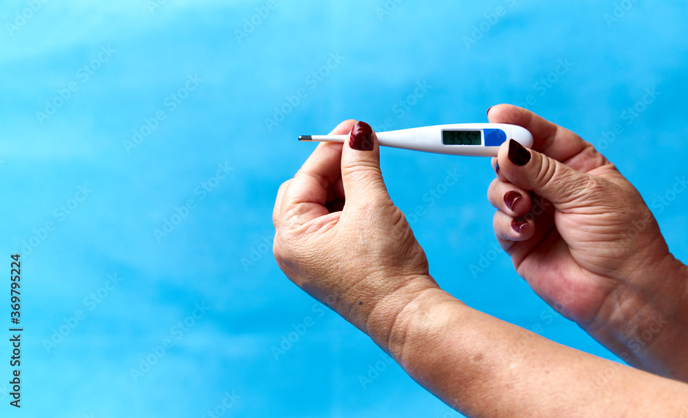 Old woman hands holding digital thermometer to measure body temperature ...