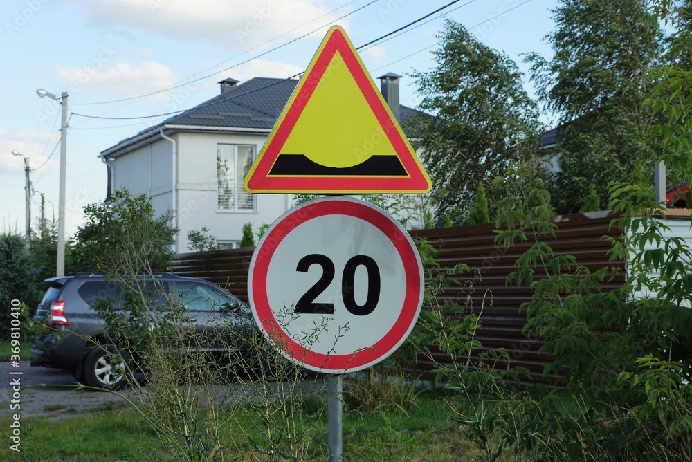 two road signs a speed bump and a speed limit on the street by the road ...