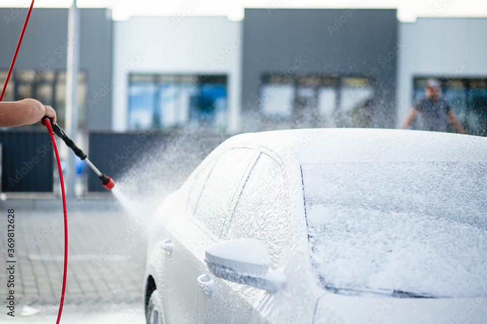 Summer car wash. Cleaning the car using high pressure water. Car wash ...