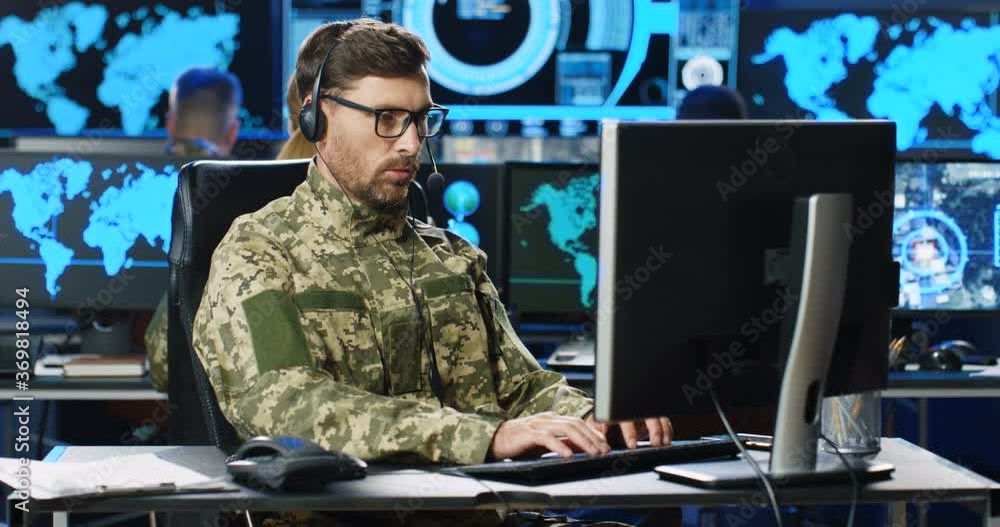 Caucasian male army officer in glasses and headset talking and working ...