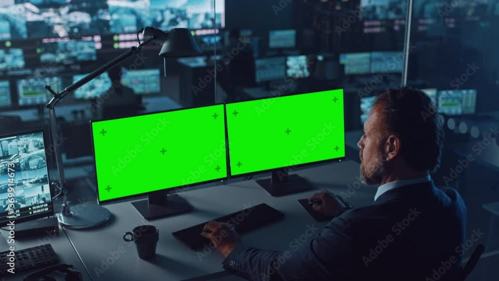 Male Officer Works on a Computer with Two Green Screen Mock Ups in ...