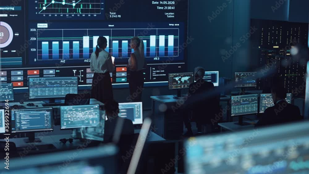 Two Software Engineers Talking Next to a Big Screen in a Modern ...