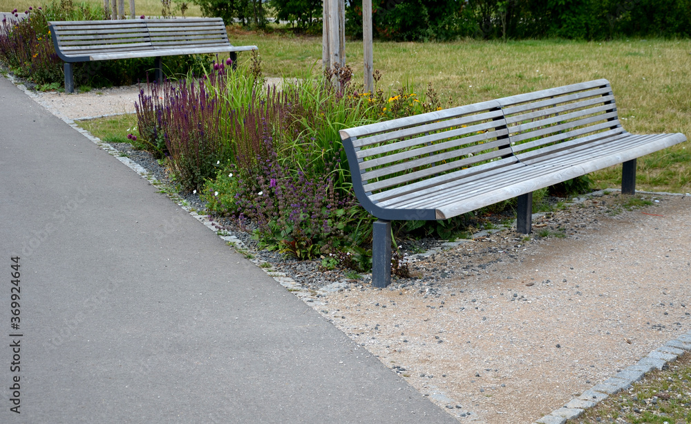 wooden modern park bench with a metal relief structure on one leg ...