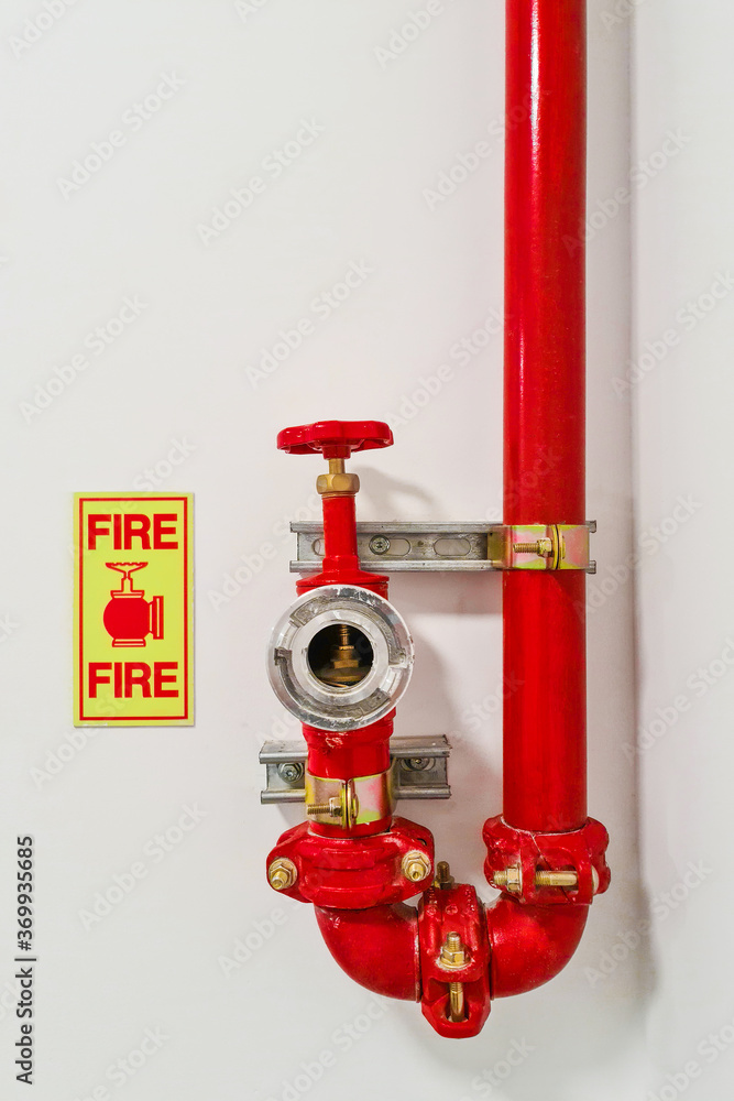Red fire hydrant inside building on white wall with information sign ...