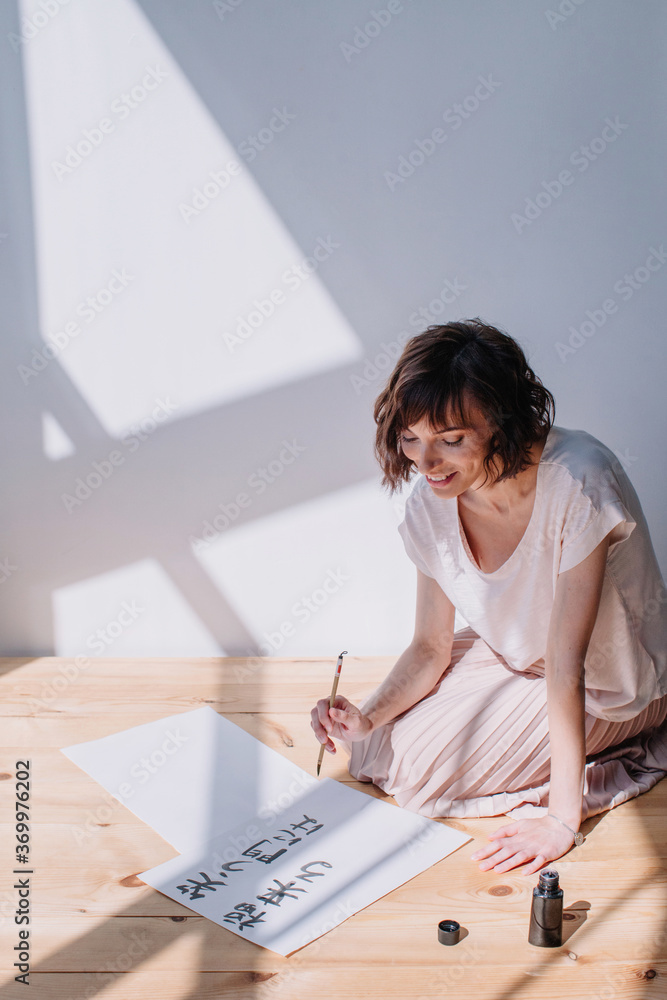 Lovely brunet female practicing calligraphy Stock Photo | Adobe Stock