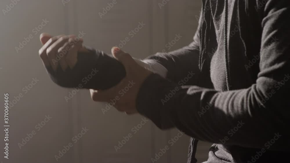 Profile portrait of Muay Thai fighter putting on hand wraps while ...