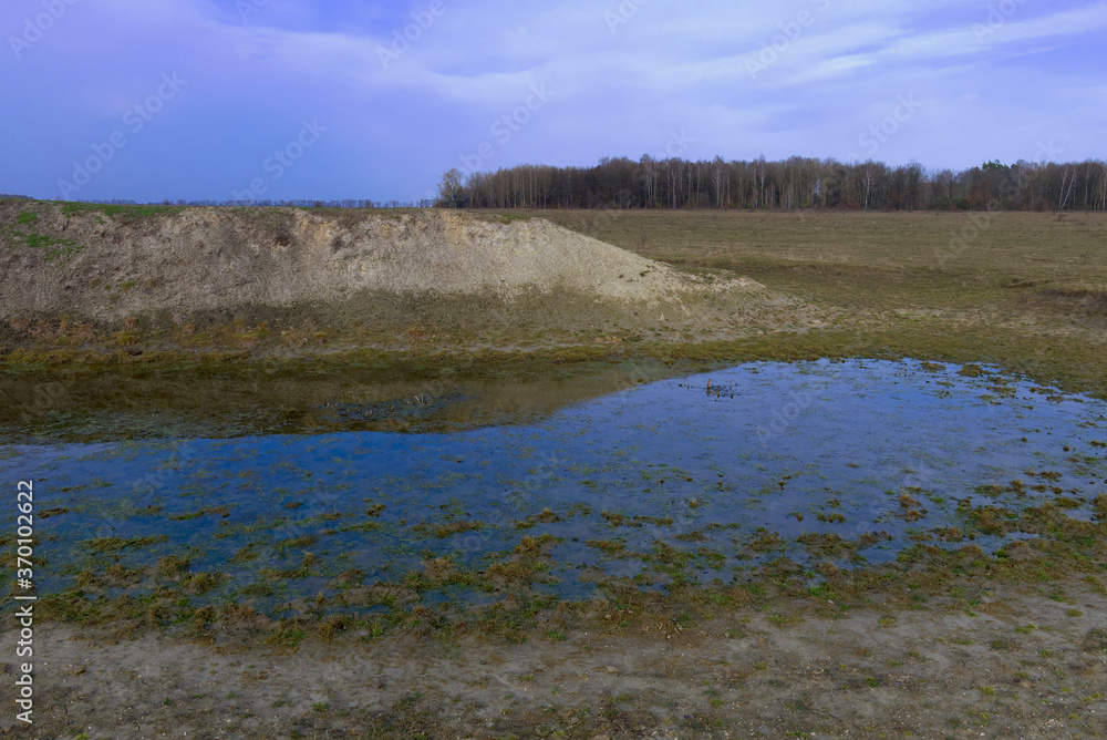 The exposed bottom of a dry pond. A shallow water body. A steep slope ...