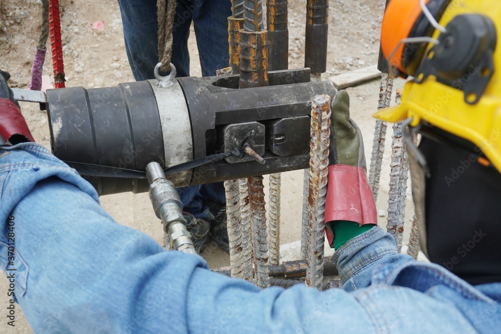 Worker is using a hydraulic press to squeeze the coupler to connect the ...