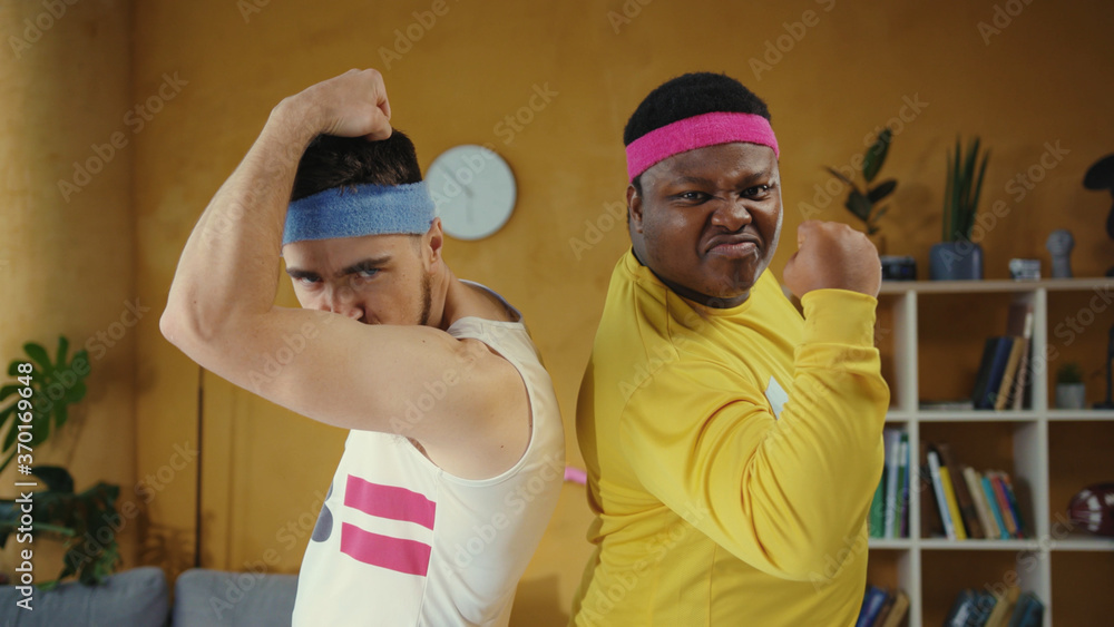 Two attractive funny fitness beginners showing masculine strength at ...