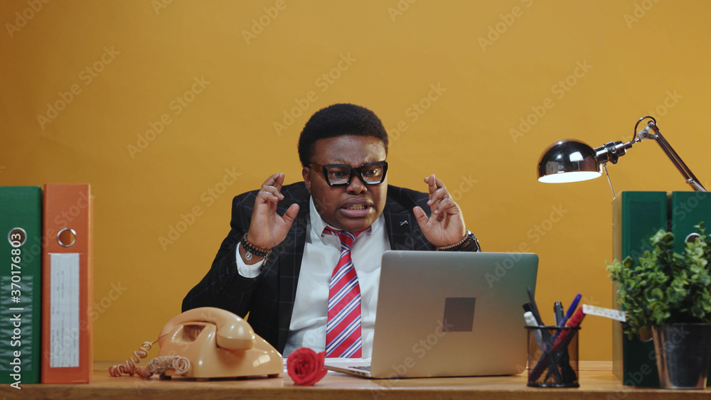 Excited black office executive playing computer game on laptop crossing ...