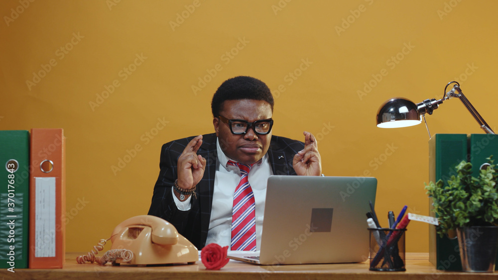 Excited black office executive playing computer game on laptop crossing ...