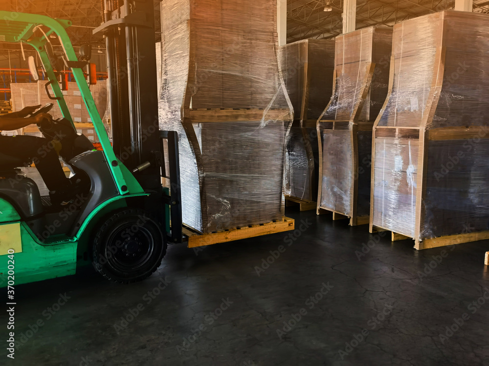 Worker driving forklift loading and unloading shipment carton boxes and ...