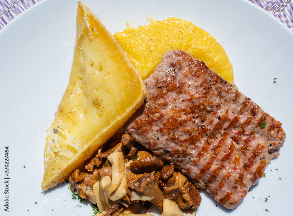 Traditional Italian mountain dish. Polenta, cheese, salami and ...