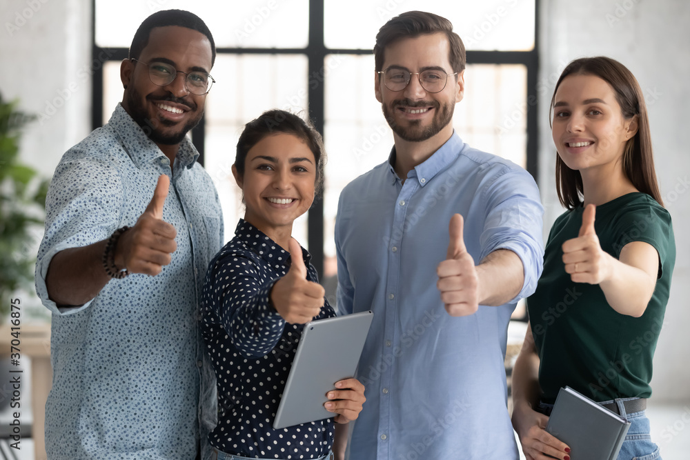 Smiling diverse employees team showing thumbs up, looking at camera ...