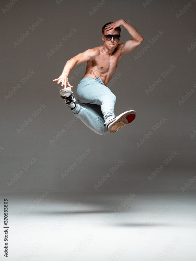 Cool young guy breakdancer dancing hip-hop and jump in studio. Dance ...