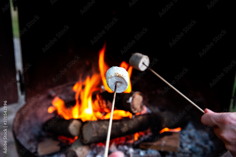 Person roasting over fire flames a marshmallows over campfire at night ...