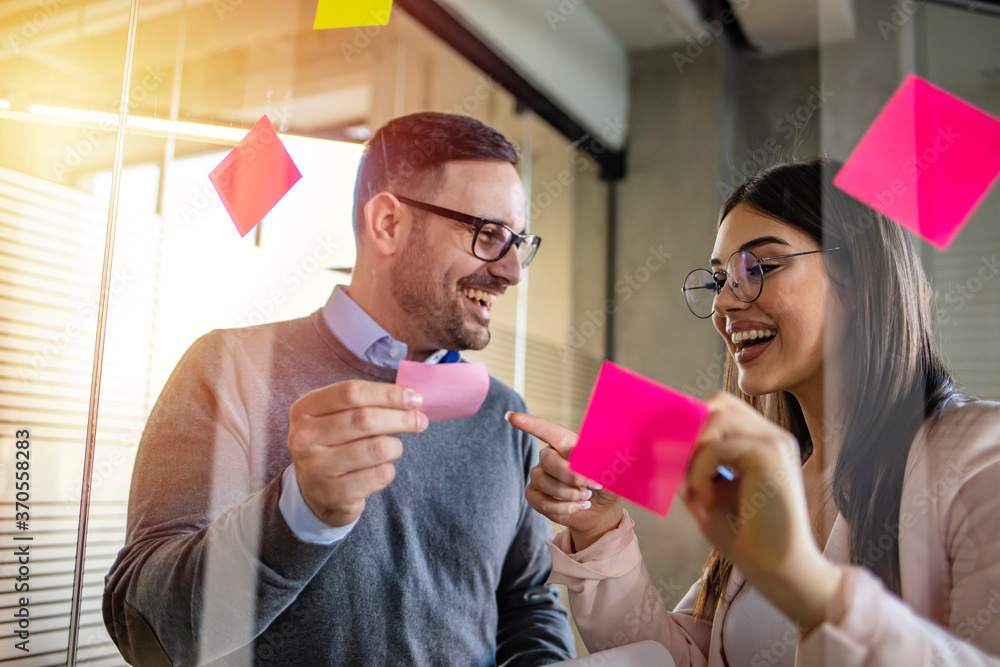 Business people looking at post it notes on notice board. Brainstorming ...