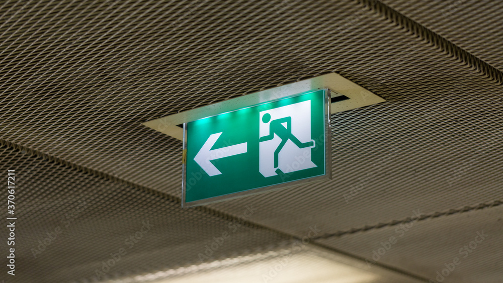 Illuminated emergency exit sign. Green sign with white arrow and figure ...
