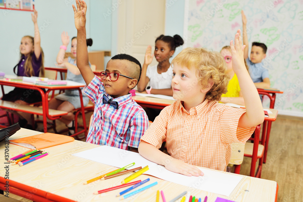 Small children school children smile and hold their hand up for a ...