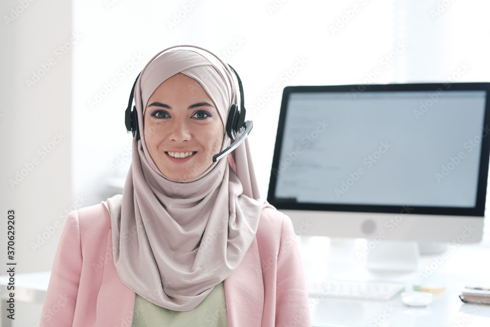 Portrait of positive beautiful young Muslim woman in hijab answering ...