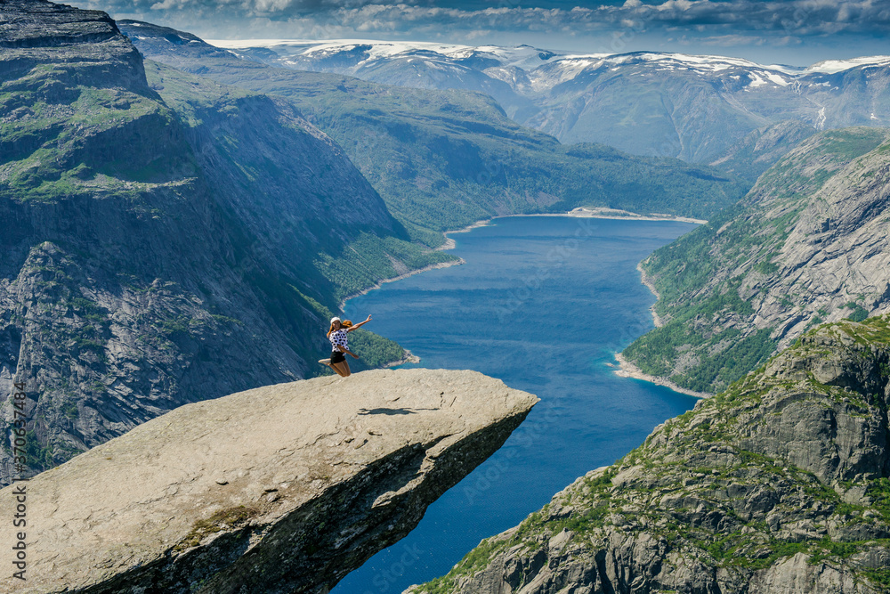 Girl sitting on the edge of a rocky cliff. Extreme tourism. Trolltunga ...