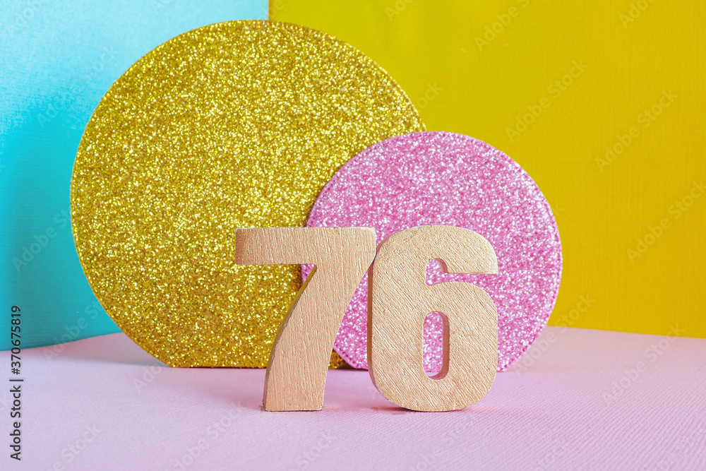 the gold number "76" on a multicolored blue-yellow-pink background and ...