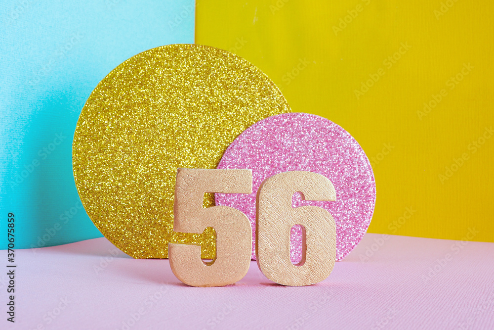 the gold number "56" on a multicolored blue-yellow-pink background and ...