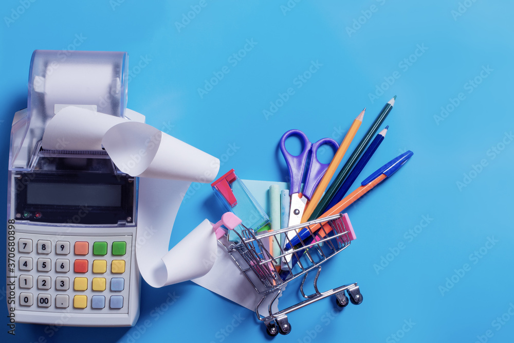 Top view photo of shopping trolley with colorful stationery and cash ...